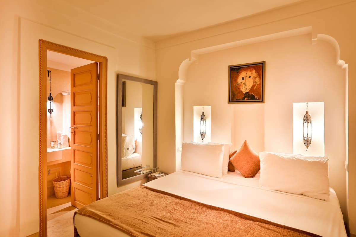 Quarto com uma cama grande, uma porta de madeira, um espelho e um quadro na parede.