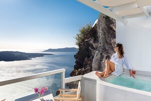 Uma pessoa relaxando em uma banheira com vista para o mar e falésias.