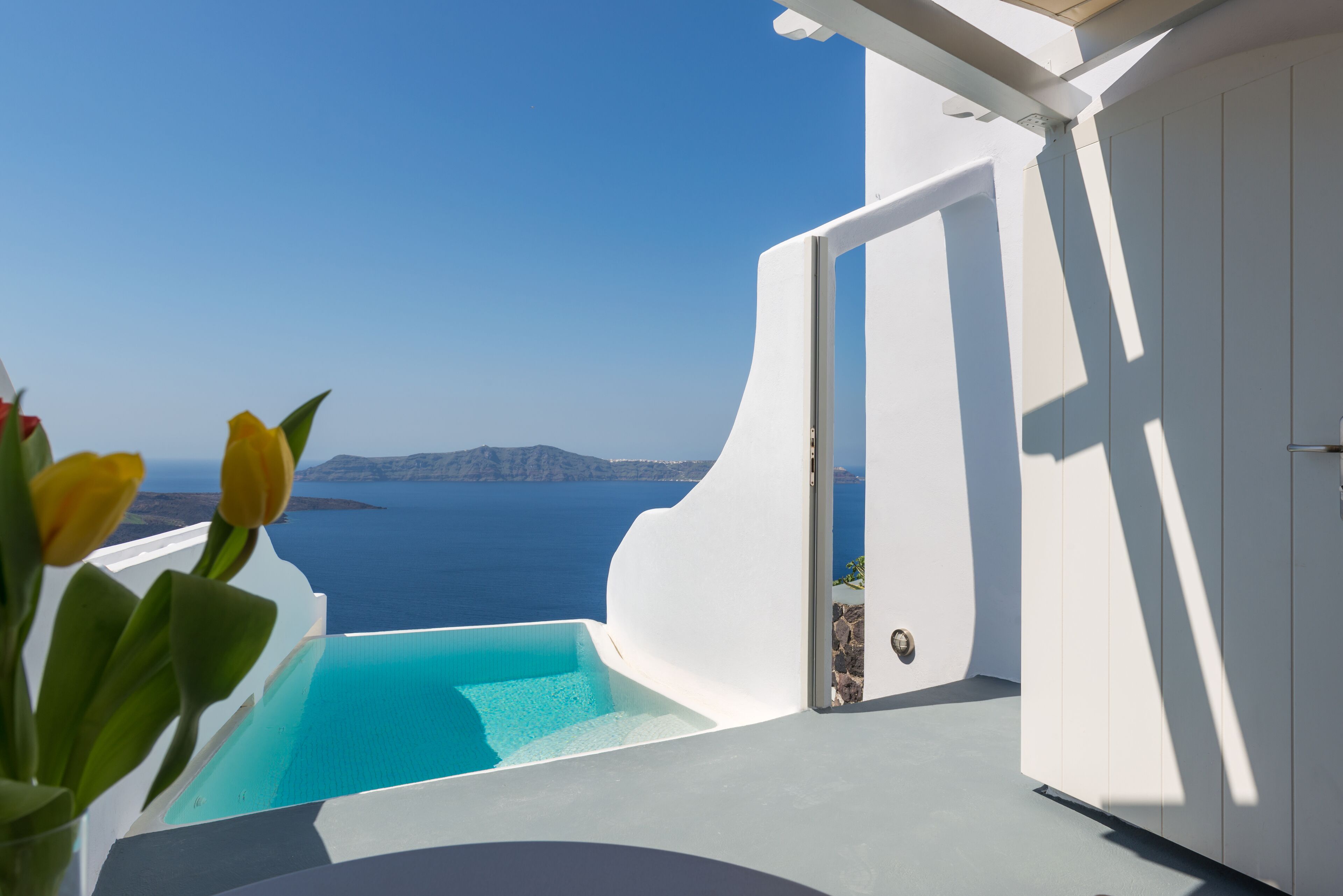 Edifício moderno branco com piscina e vista para o mar.