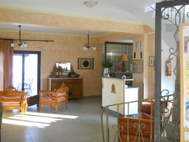 Ampla sala de estar com sofá de madeira, mesa de jantar e área de cozinha com bancada e armários.