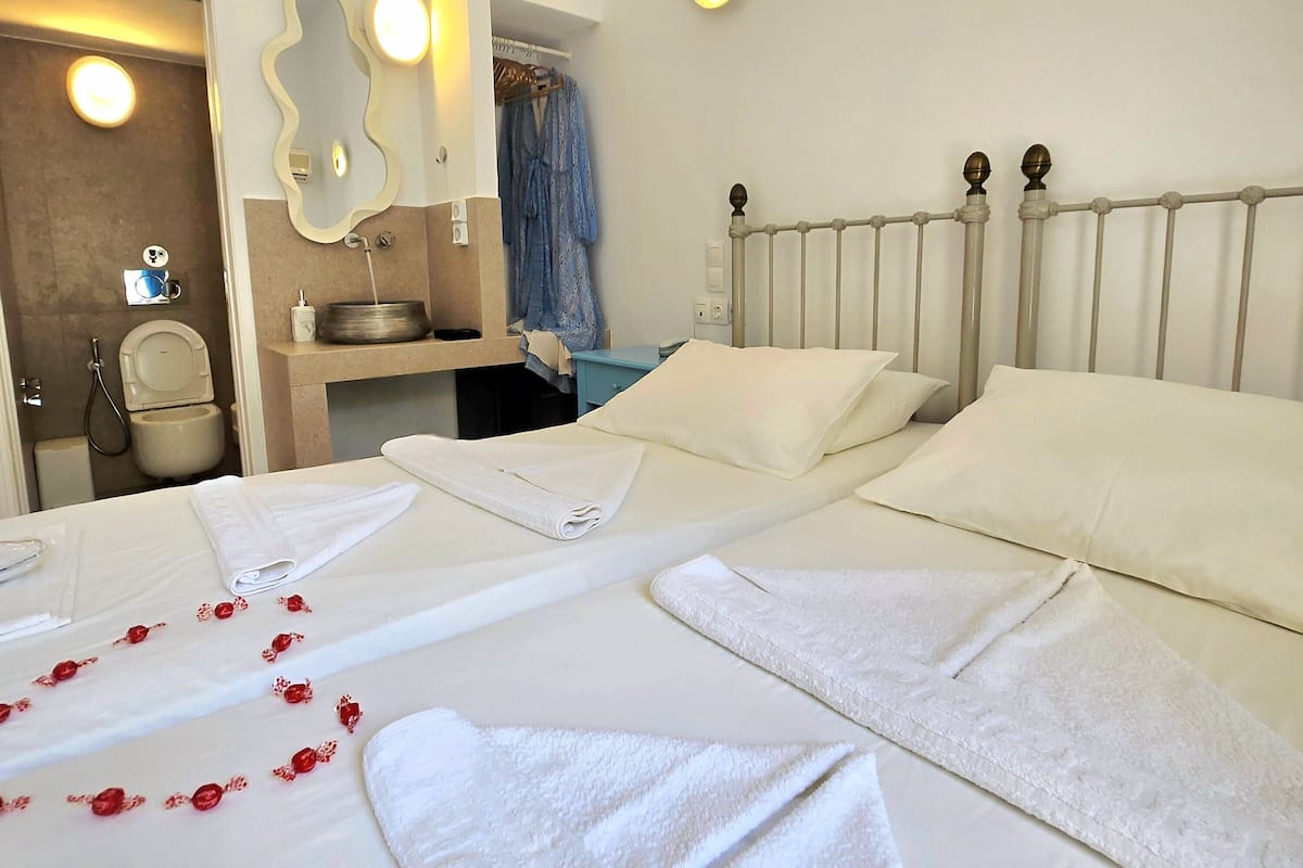 Quarto de hotel com cama, banheiro com vaso sanitário, pia e espelho.
