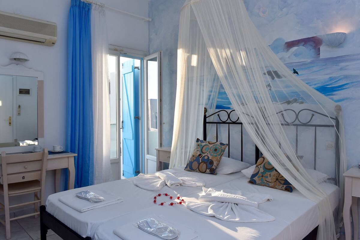 Quarto com cama, escrivaninha, cadeira e espelho.