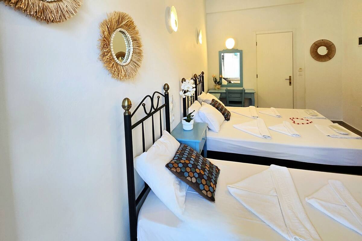 Quarto de hotel com duas camas, uma escrivaninha, uma cadeira, um espelho e uma televisão.