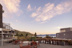 Terraço com área de estar ao ar livre, vista para um lago e paisagem montanhosa.
