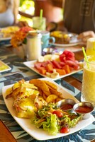 Uma mesa de jantar com pratos de comida, incluindo salada, grelhados e frutas.