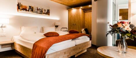 Quarto com cama de madeira, mesa de cabeceira, luminária de parede, teto de madeira e espelho.