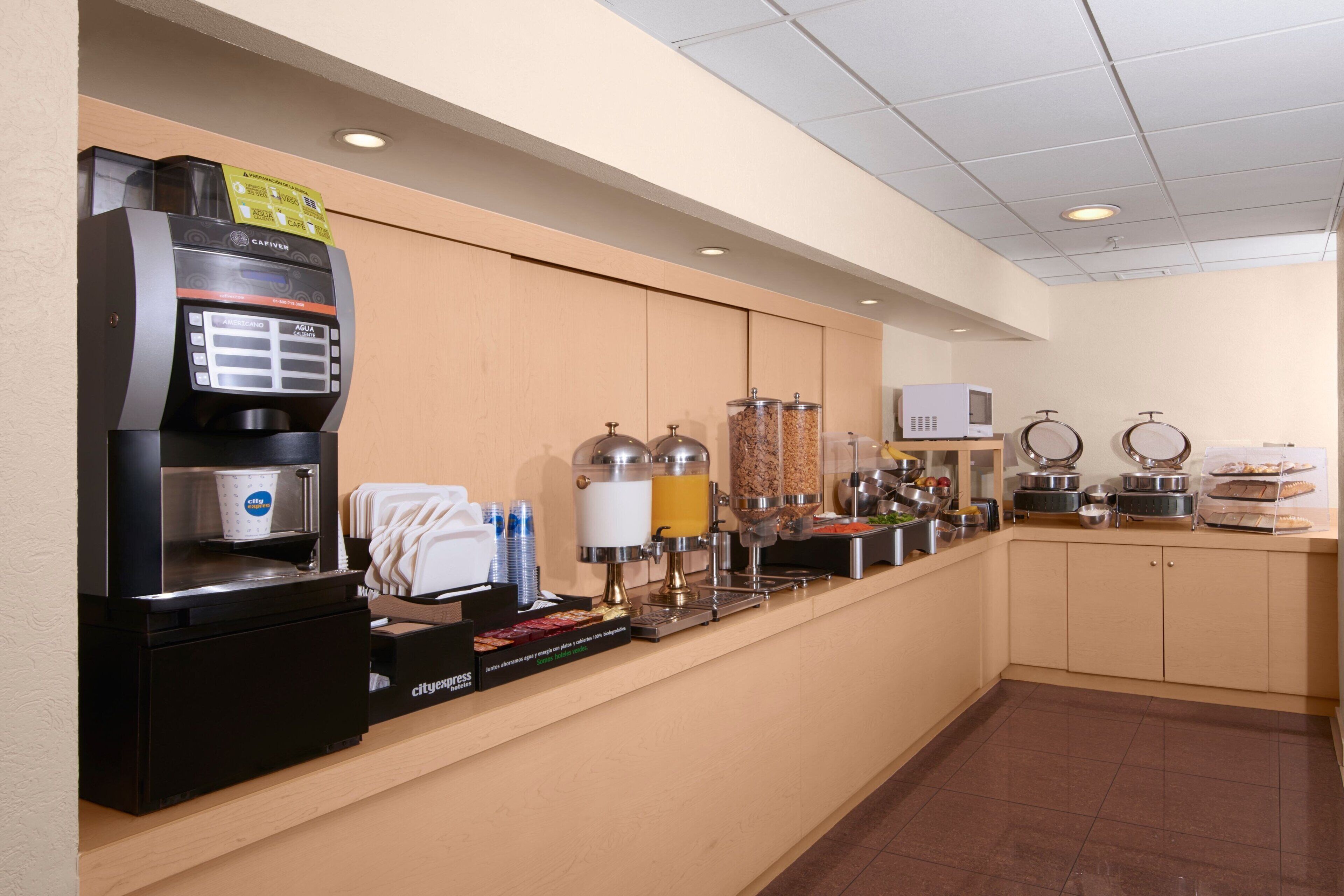 Um buffet de café da manhã com máquina de café, dispensadores de bebidas e micro-ondas.