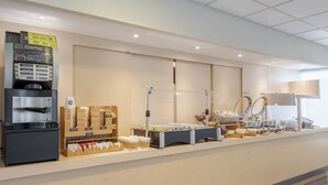 Uma área de buffet com máquina de café, vários recipientes de comida e um dispensador de bebidas para autoatendimento.