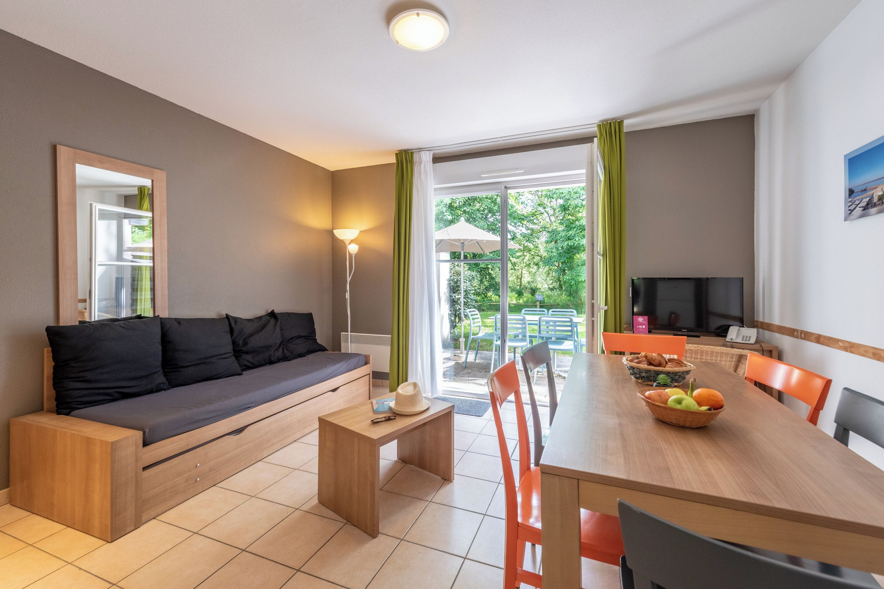 Uma sala de estar moderna com sofá, mesa de jantar e televisão.