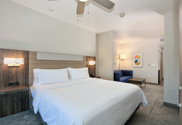 Quarto de hotel com cama grande, mesas de cabeceira, ventoinha no teto e luminária fixada na parede.