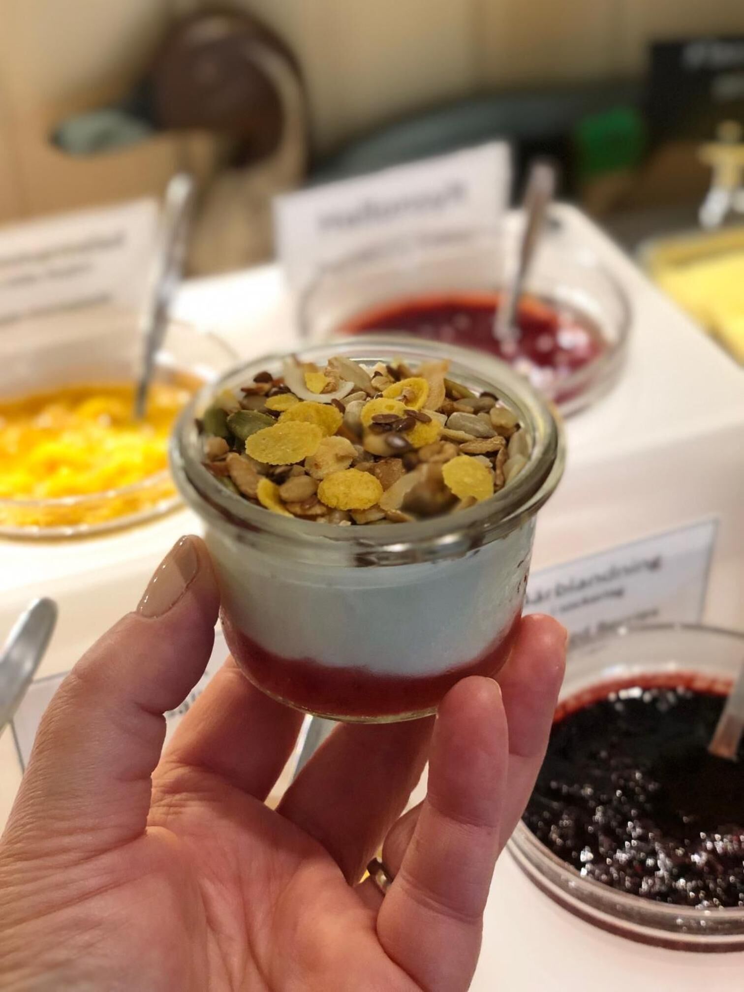 Uma mão segurando um pote com mistura de frutos secos e sementes.