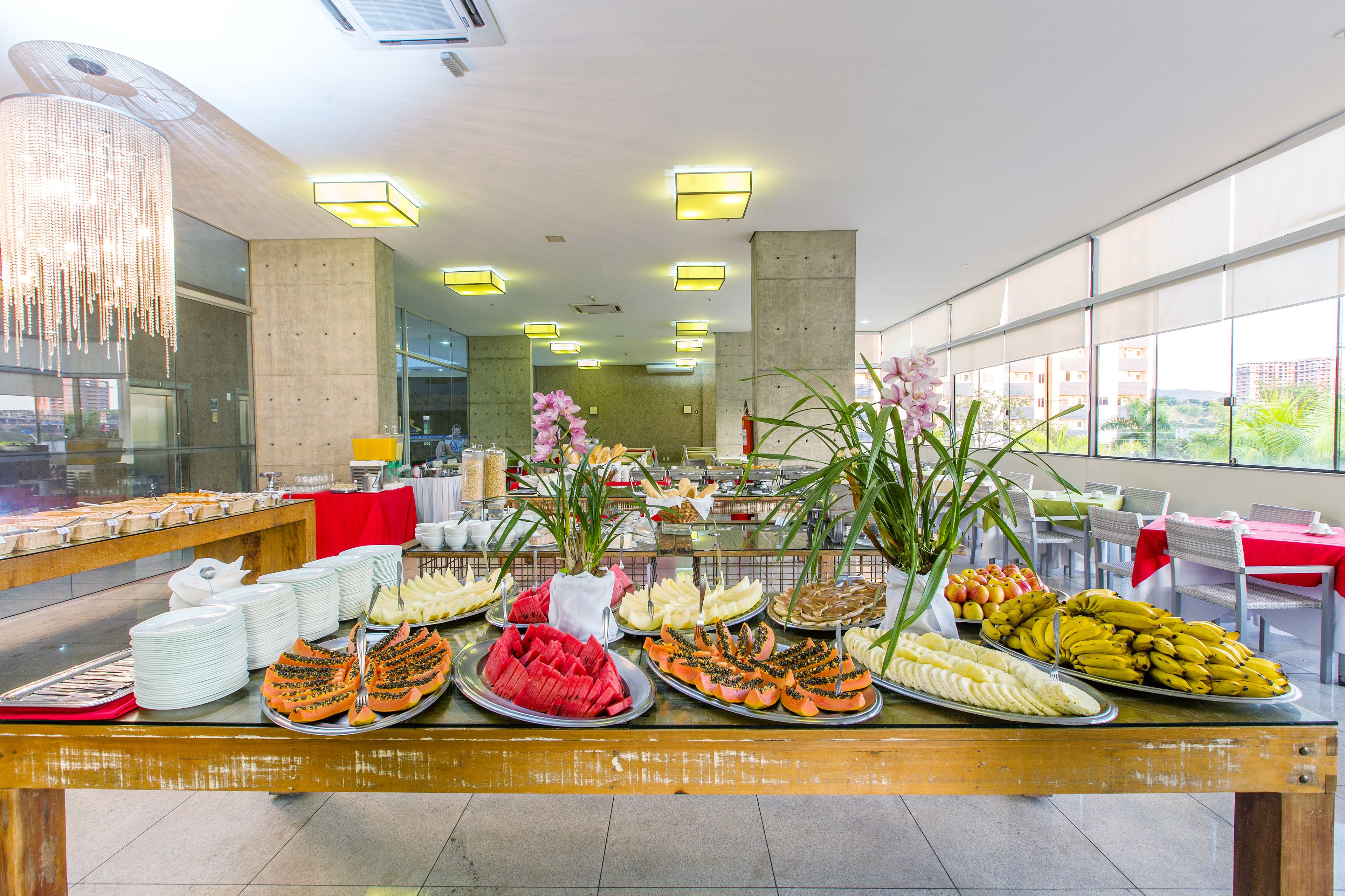 Buffet com diversos alimentos e uma grande janela com vista para edifícios.