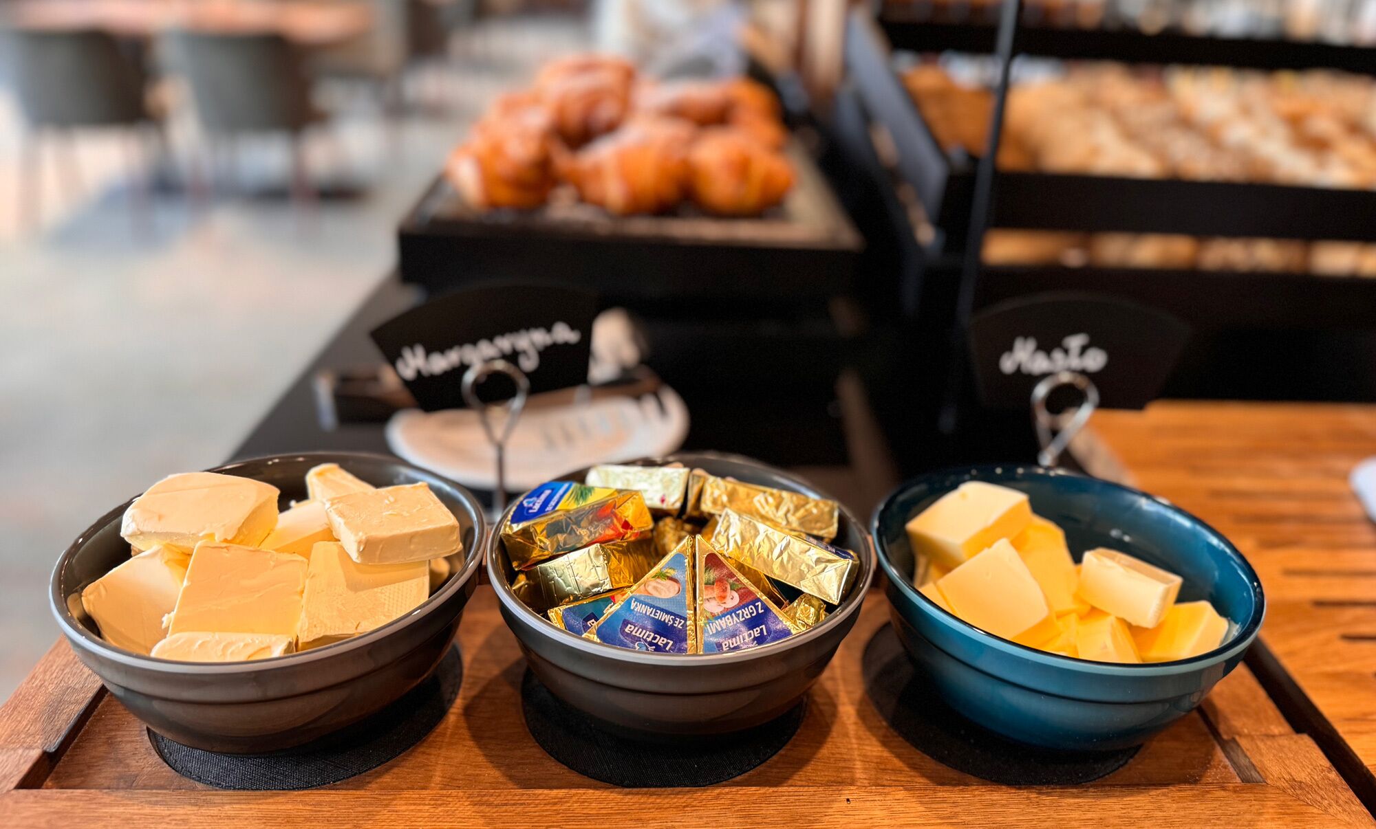 Três tigelas de queijo e chocolate sobre uma mesa de madeira.