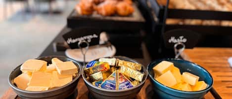 Três tigelas de queijo e chocolate sobre uma mesa de madeira.