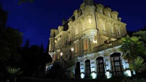 Um edifício histórico com várias torres e janelas em arco, iluminado à noite.