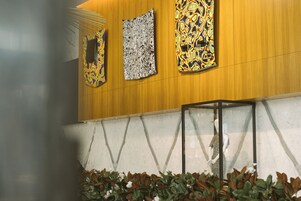 Interior moderno com paredes de painel de madeira, piso de mármore e um manequim em vitrine de vidro.