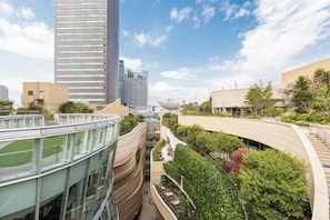 Um edifício moderno com arquitetura curvilínea, fachada de vidro e um jardim no terraço.