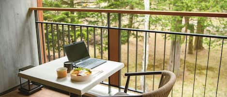 Uma varanda com uma mesa, um laptop e uma cadeira.