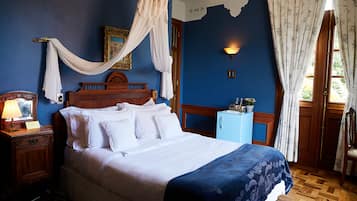 Quarto com cama, cabeceira de madeira, mesa de cabeceira e cortinas.