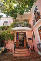 Um edifício rosa com varanda, escadaria e porta com painéis de vidro.