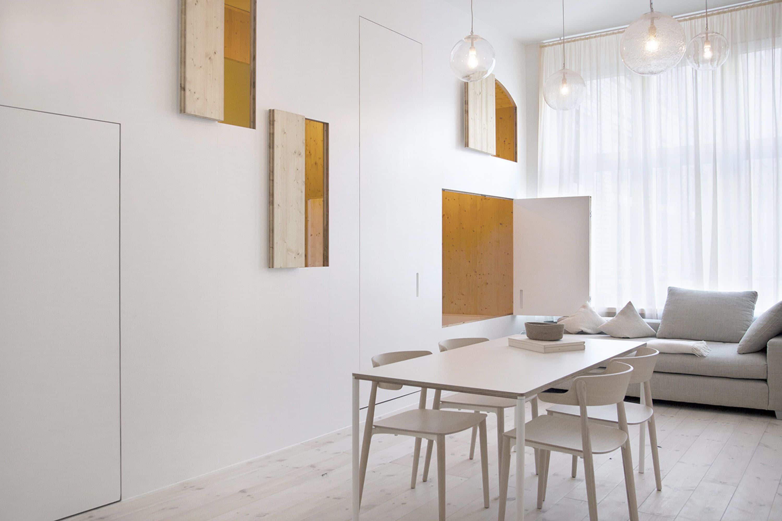 Uma sala de estar moderna com um sofá branco, uma mesa de jantar com cadeiras e obras de arte nas paredes.