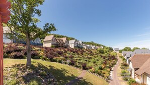 Zona residencial com casas numa encosta, um caminho sinuoso e uma árvore em primeiro plano.