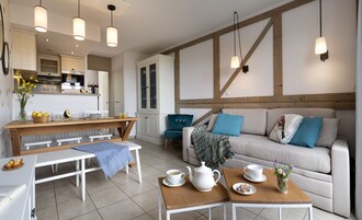 Uma sala de estar moderna com um sofá, uma mesa de jantar e uma área de cozinha ao fundo.