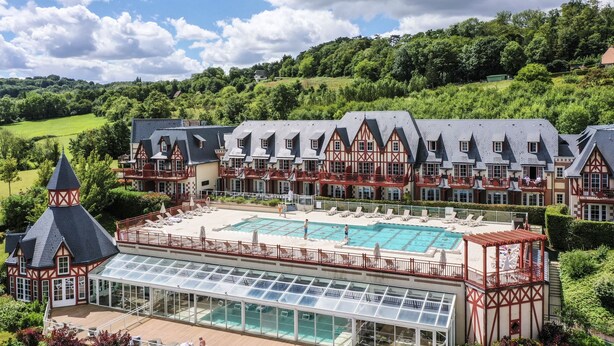 Um hotel grande com piscina, vários quartos de hóspedes e uma estufa de vidro.