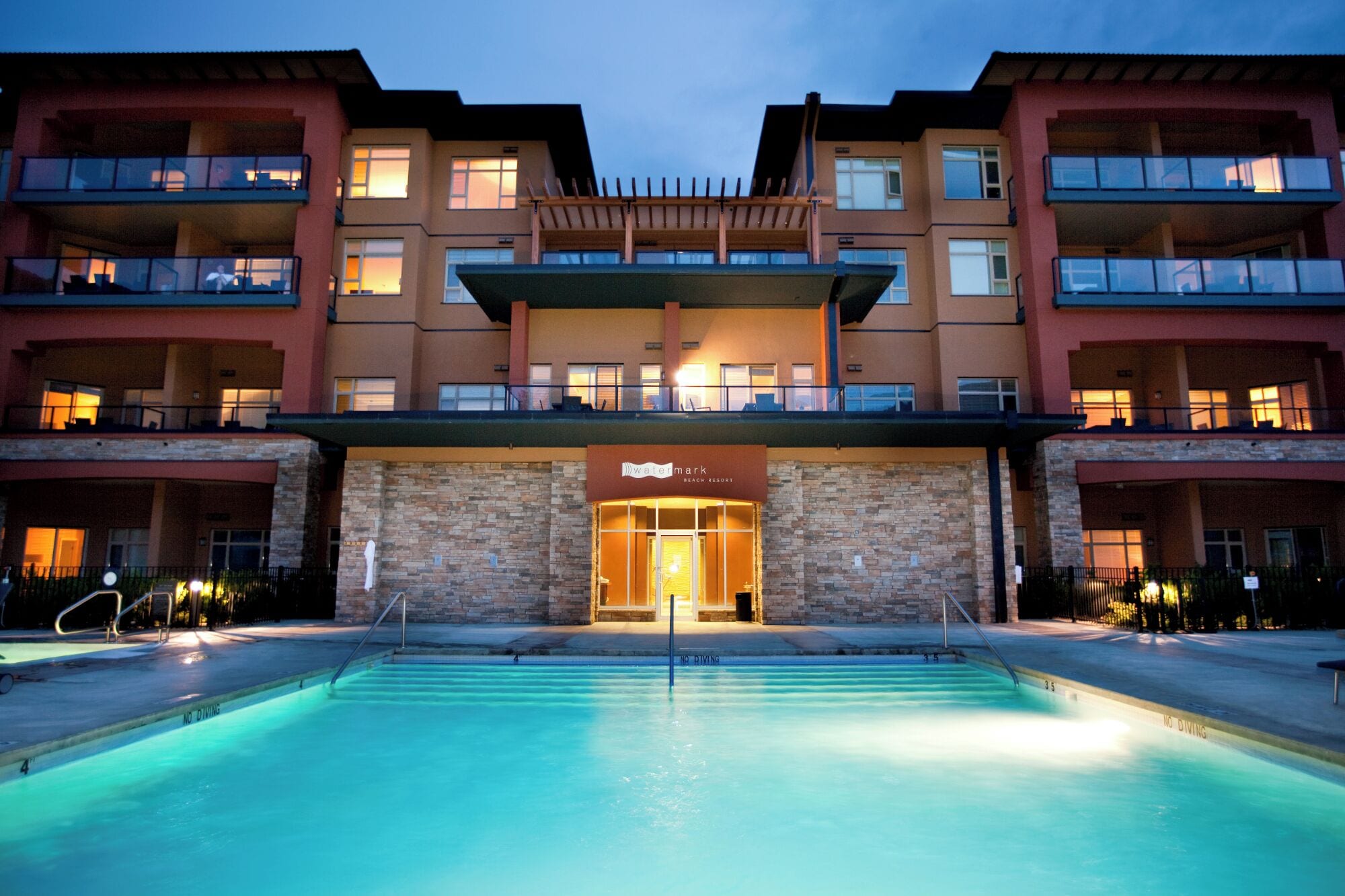 Um hotel com piscina, várias varandas e fachada de pedra.