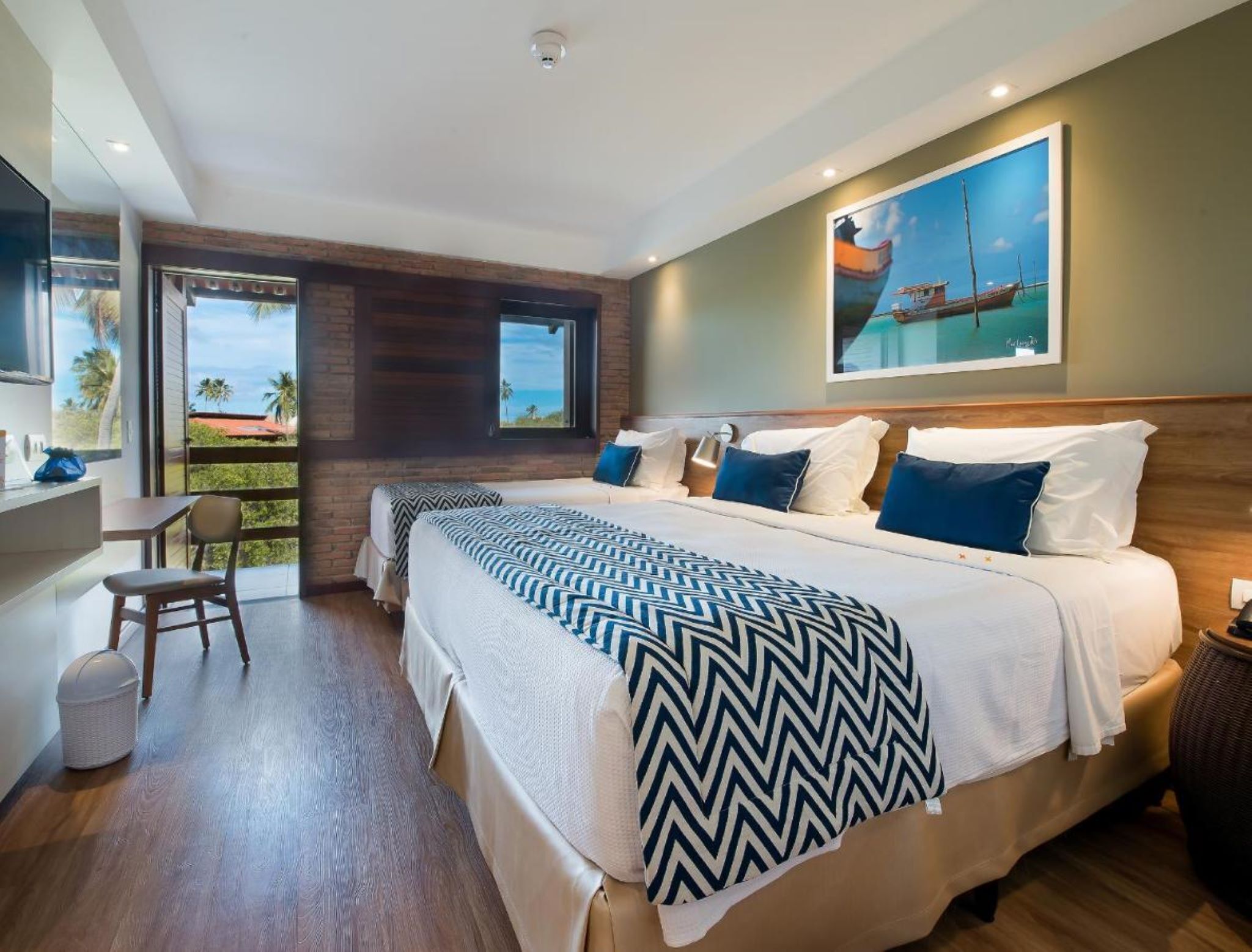 Quarto de hotel com uma cama grande, uma escrivaninha e vista para o oceano.