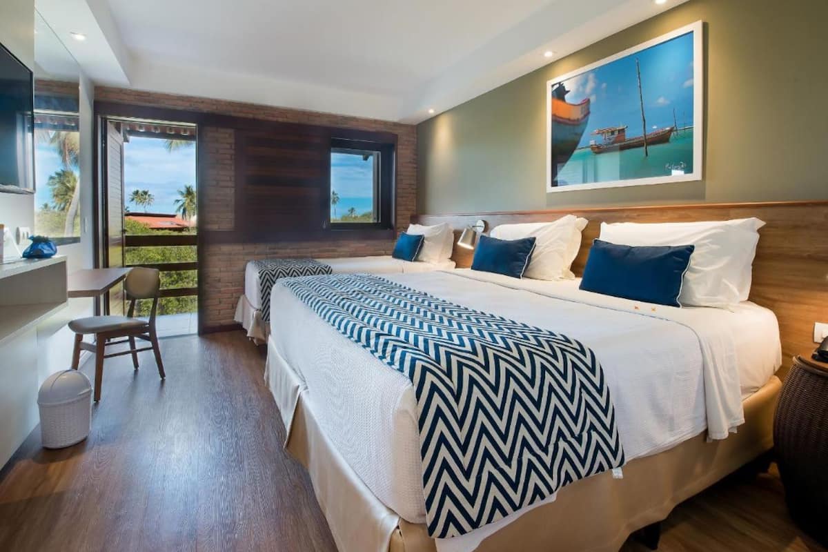 Quarto de hotel com uma cama grande, uma escrivaninha e vista para o oceano.