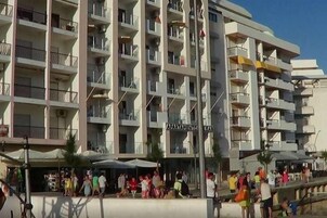 Um hotel com vários andares, varandas, área de estar externa e um letreiro de restaurante visível.