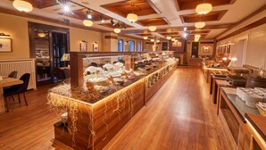 Uma área de buffet com um balcão comprido, iluminação pendente e piso de madeira.
