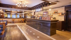 Uma área de bar com um balcão longo, assentos e um candelabro.