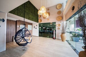 Um interior moderno com uma cadeira suspensa, uma parede verde e uma planta grande.