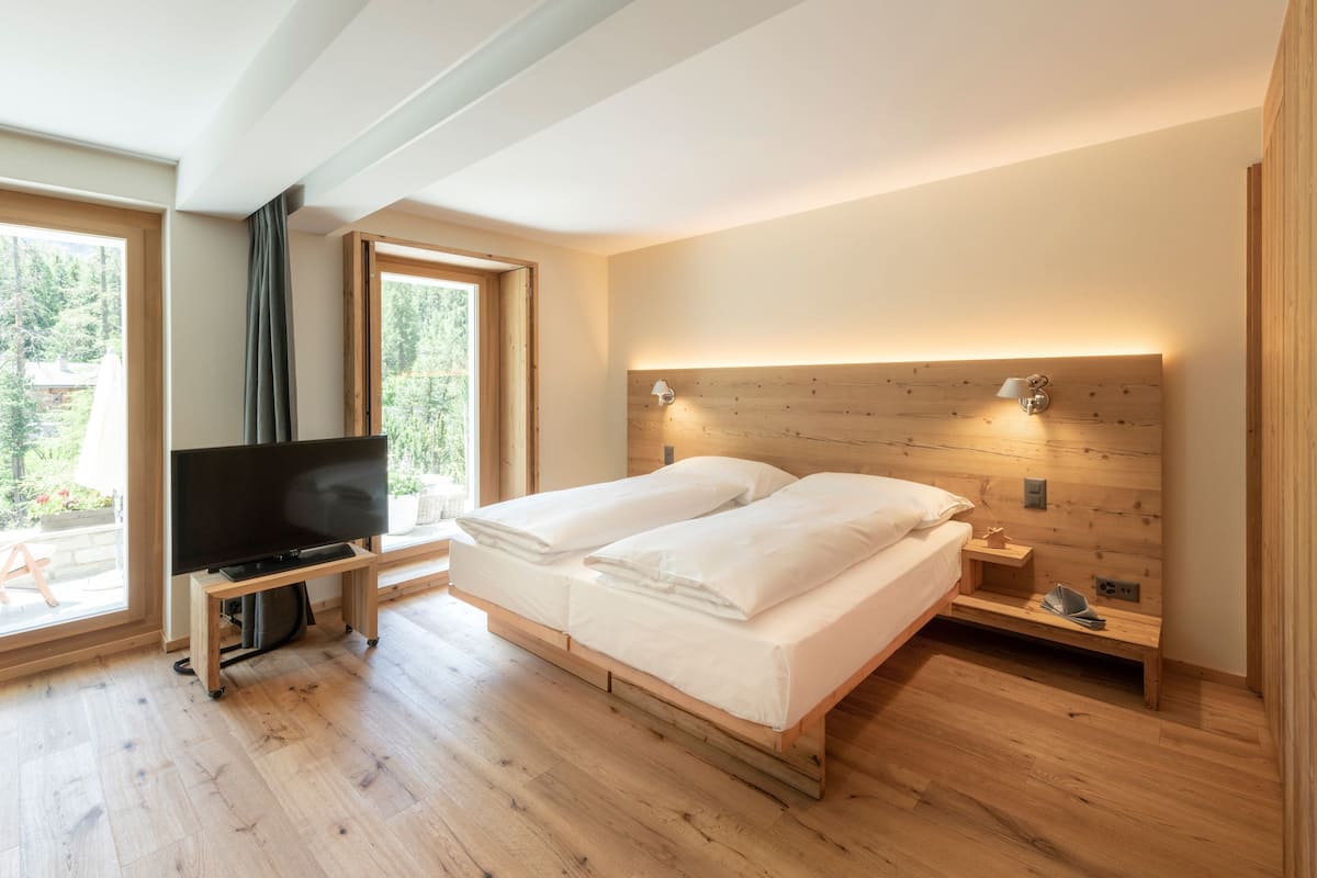 Quarto com cama, televisão, abajures e janela com cortinas.