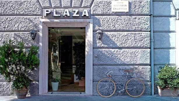 Um edifício com uma placa indicando "PLAZA" e uma bicicleta estacionada na frente.