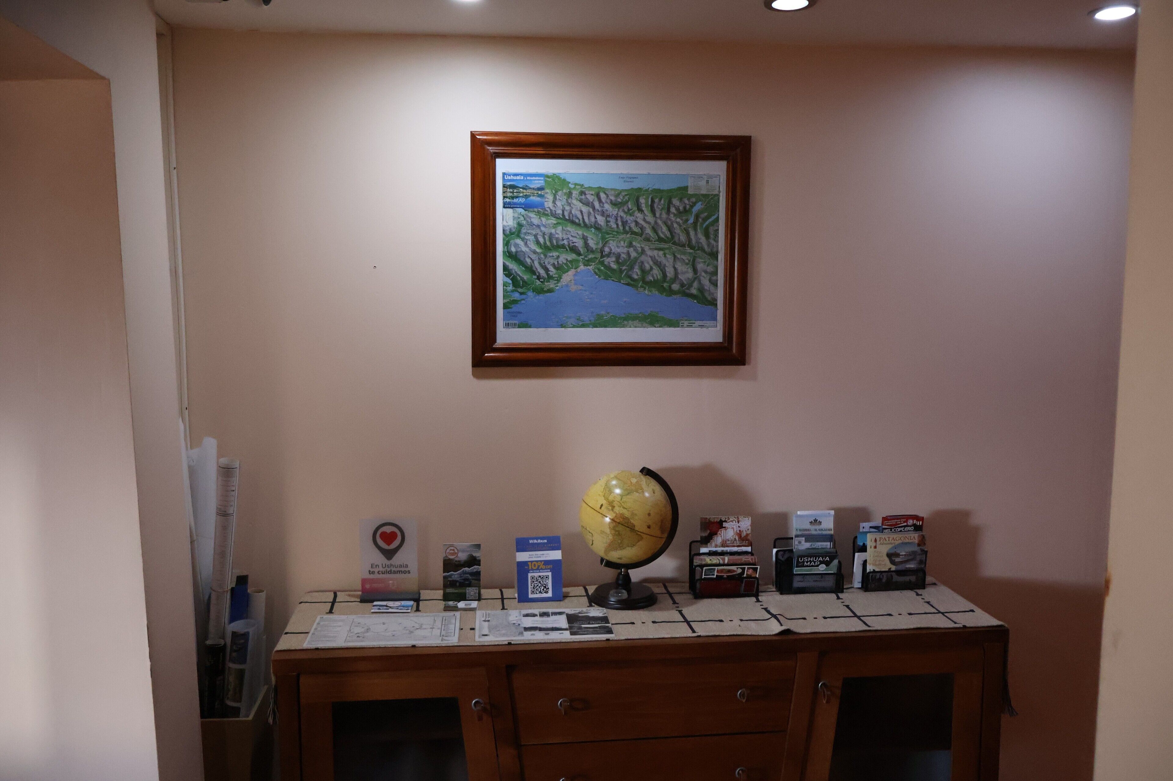 Uma mesa com um mapa emoldurado, um globo e vários livros e caixas.