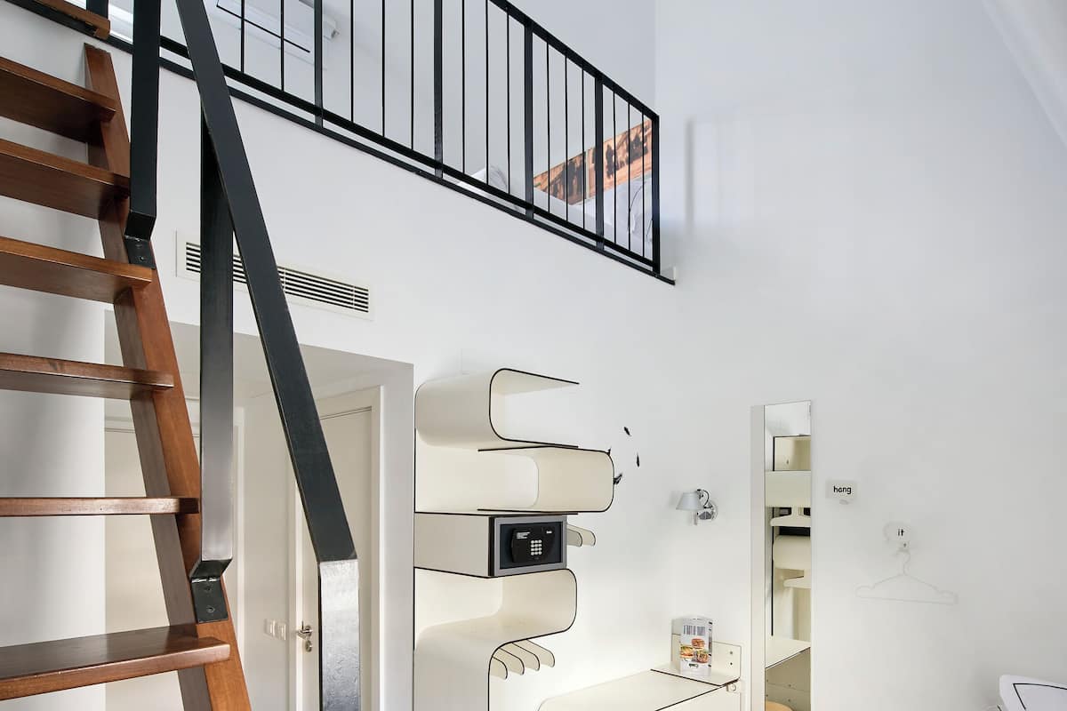 Quarto moderno com escada de madeira, uma mesa branca, uma cadeira e uma cama com tapete verde.