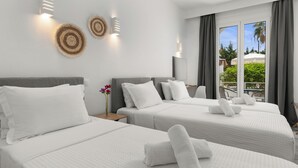 Quarto de hotel com três camas, uma janela grande com vista e luminária fixa na parede.