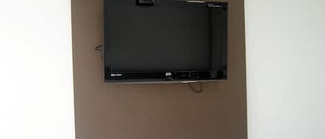 Uma televisão de tela plana fixada em uma parede marrom.