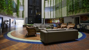 Um hall amplo com plantas pendentes, assentos confortáveis e piso revestido de azulejos.