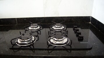 Cozinha com quatro bocas de gás em bancada preta.