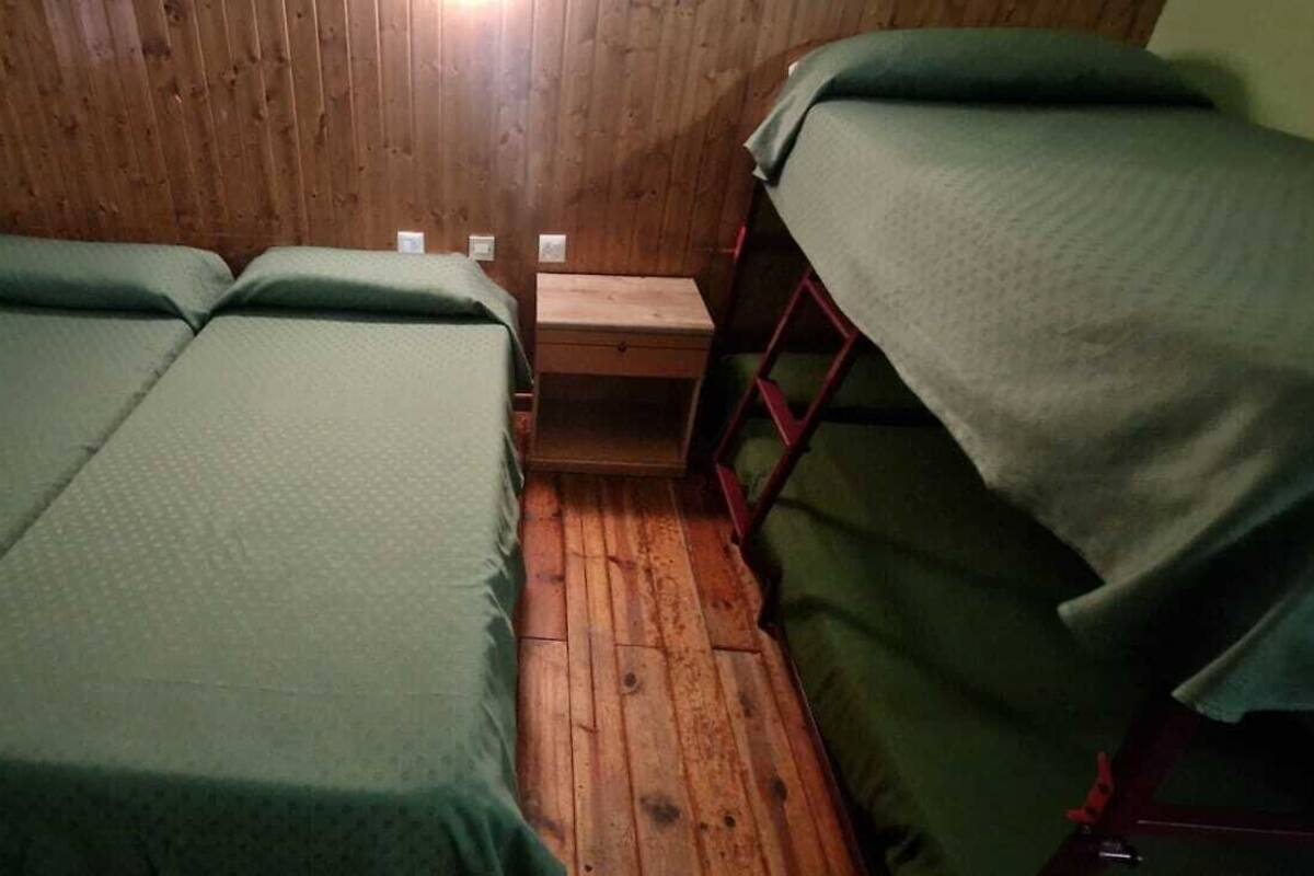 Um quarto pequeno e acolhedor com duas camas de solteiro, uma parede de madeira e uma pequena mesa de madeira.