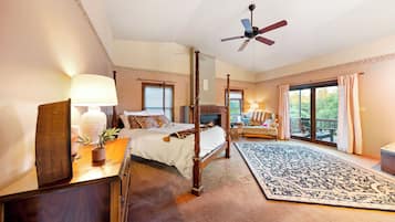 Um quarto espaçoso com uma cama grande, um ventilador de teto, uma lareira e vista para o exterior através de uma porta de correr de vidro.