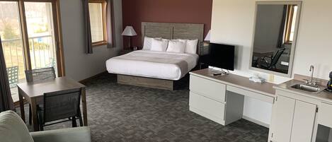 Quarto de hotel com cama, escrivaninha, cadeira e um espelho grande.