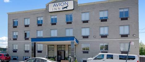 Um edifício de vários andares com uma placa indicando 'AVION INN' e uma bicicleta estacionada em frente.