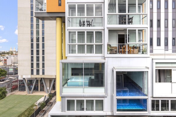 Um edifício moderno de vários andares com varandas com assentos e fachada de vidro.