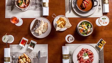 Uma mesa de jantar com diversos pratos, incluindo uma tigela de sopa, um prato de carne e uma salada, além de talheres e guardanapos.
