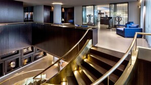 Um lobby de hotel moderno com uma escada curva, áreas de estar e decoração com um leme de navio.
